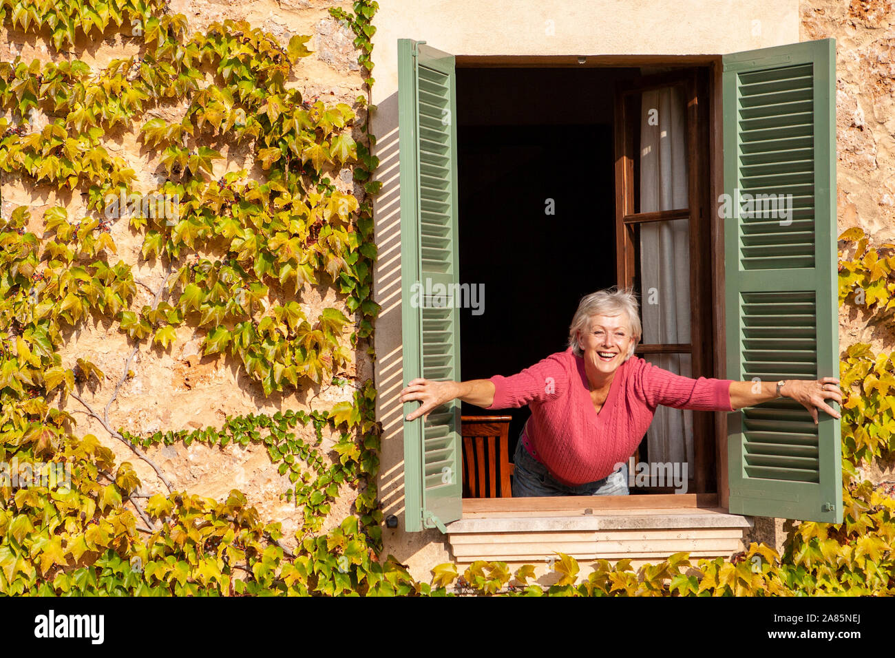 Senior woman opening the window Stock Photo - Alamy