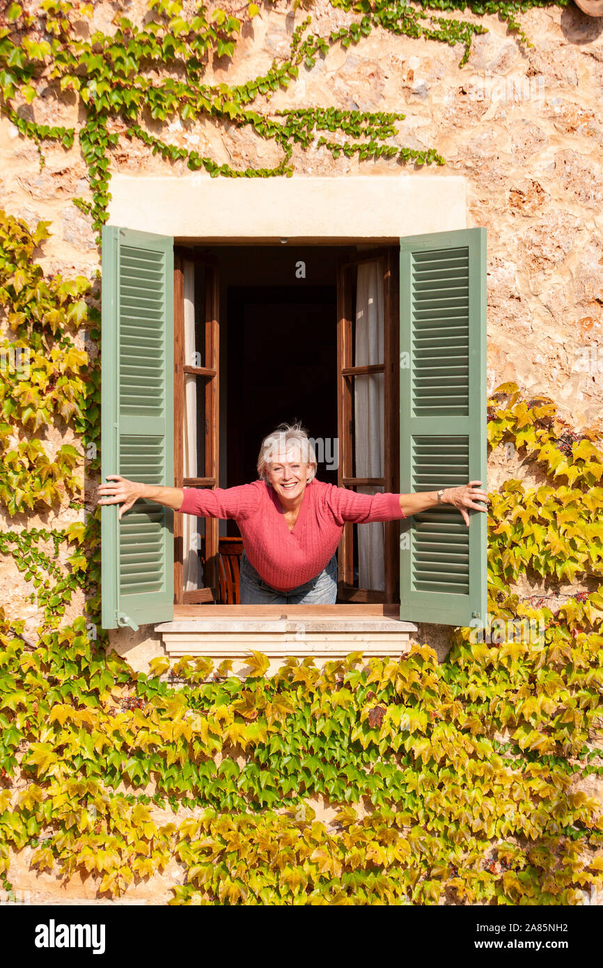 Senior woman opening the window Stock Photo - Alamy
