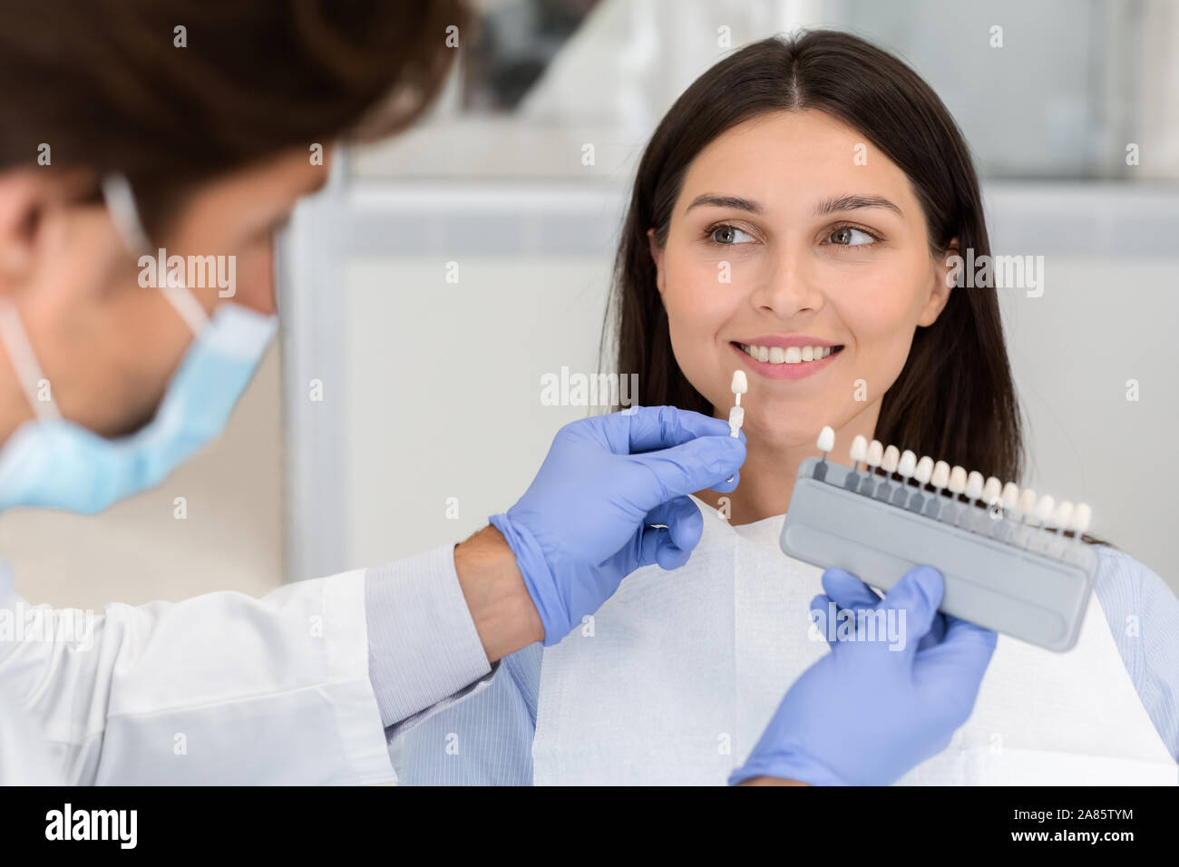 Dentist applying sample from tooth scale to smiling patient teeth Stock ...