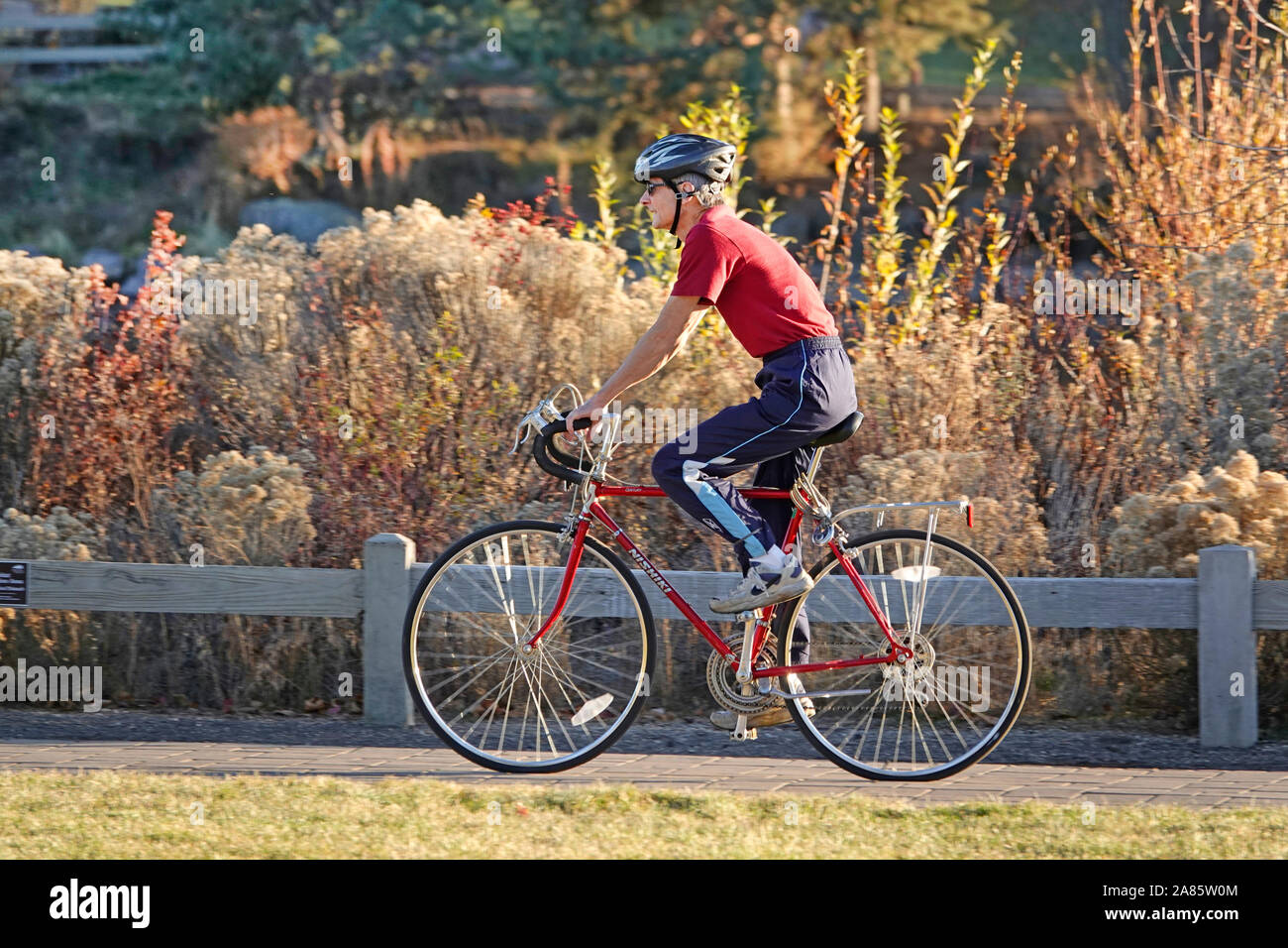 A senior bicycle rider navigates a paved path along the Deschutes River ...