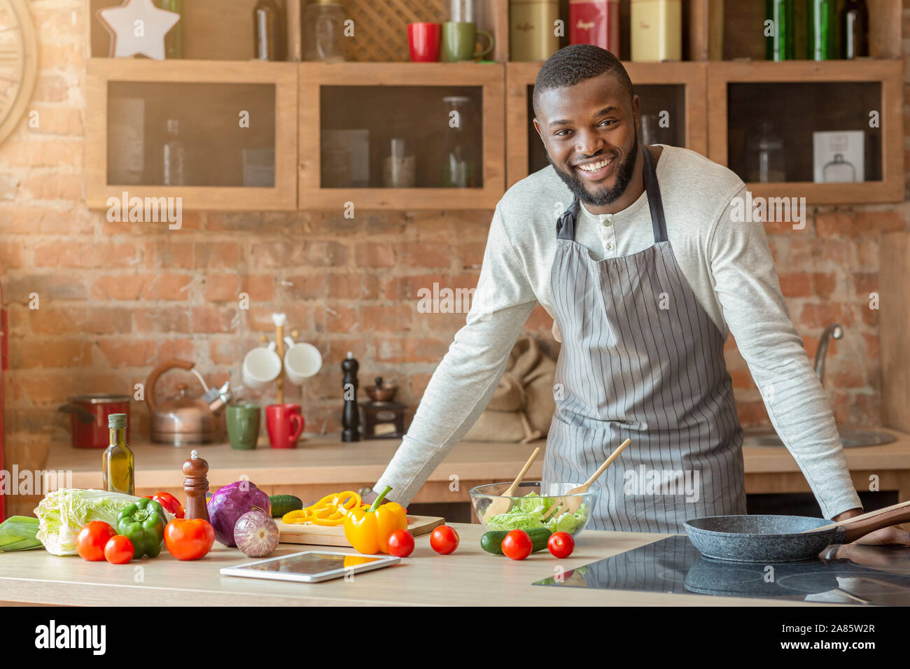 Attractive black man posing at kitchen while cooking Stock Photo - Alamy