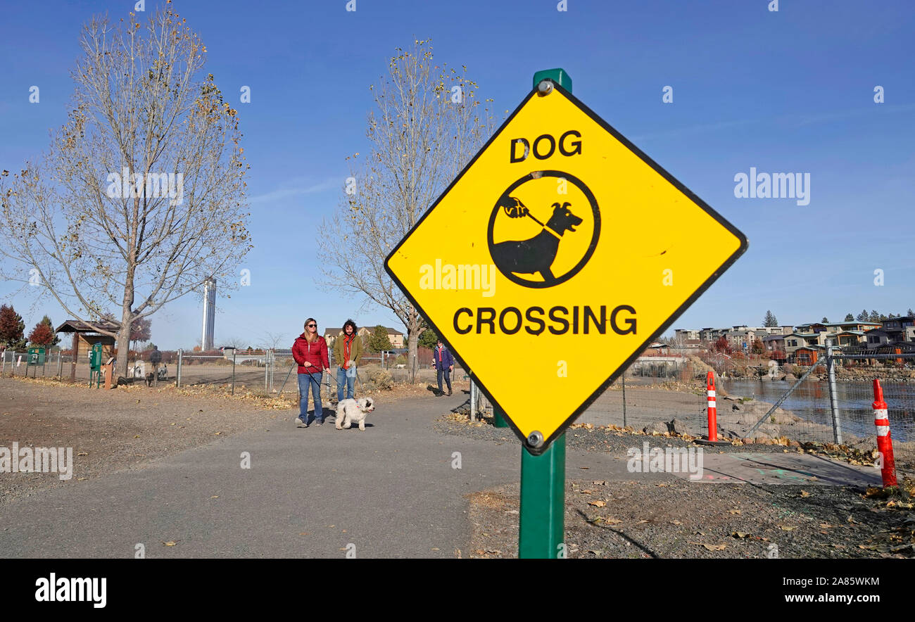 A sign marks a dog crossing area on a walking path along the Deschutes ...
