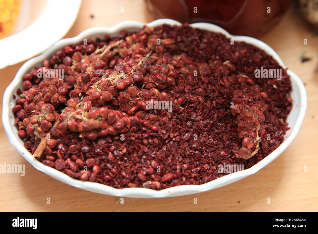 Dried sumac seasoning in a wooden bowl, top view. a handful of red ...