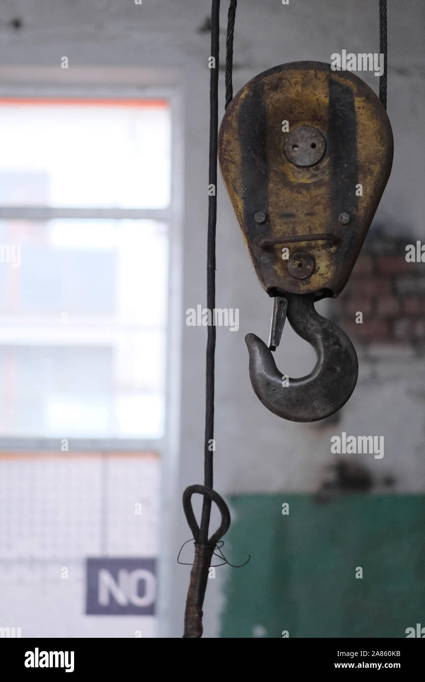 Hanging on the cables metal hook lifting device in the production room ...