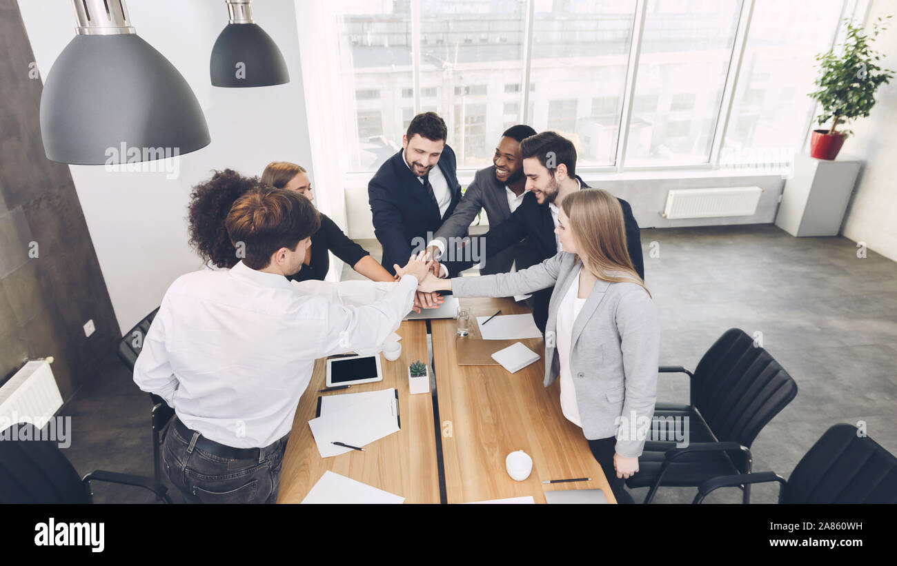 Excited colleagues joining hands involved in teambuilding activity ...