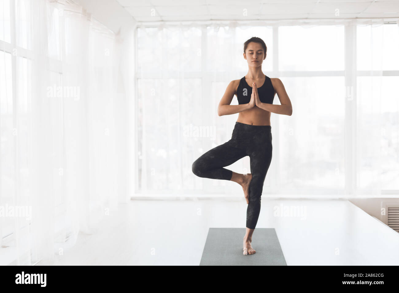 Finding right balance. Woman doing perfect tree pose Stock Photo - Alamy