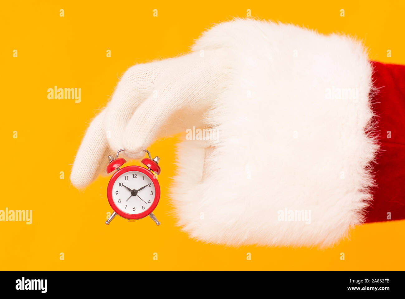 Santa holding retro red alarm clock on orange Stock Photo - Alamy