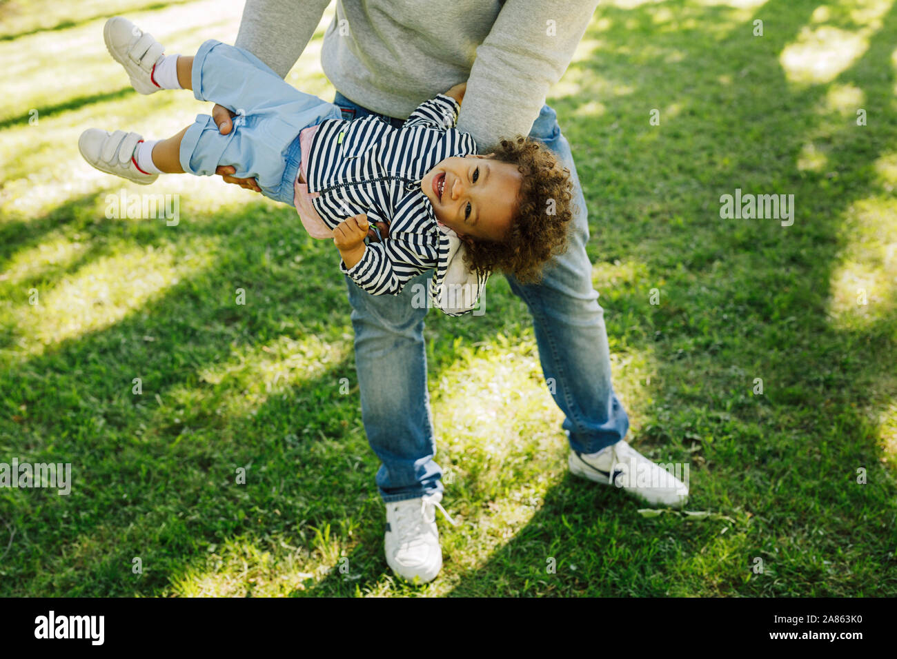 Unrecognizable man carrying little boy in hands. Father playing with ...