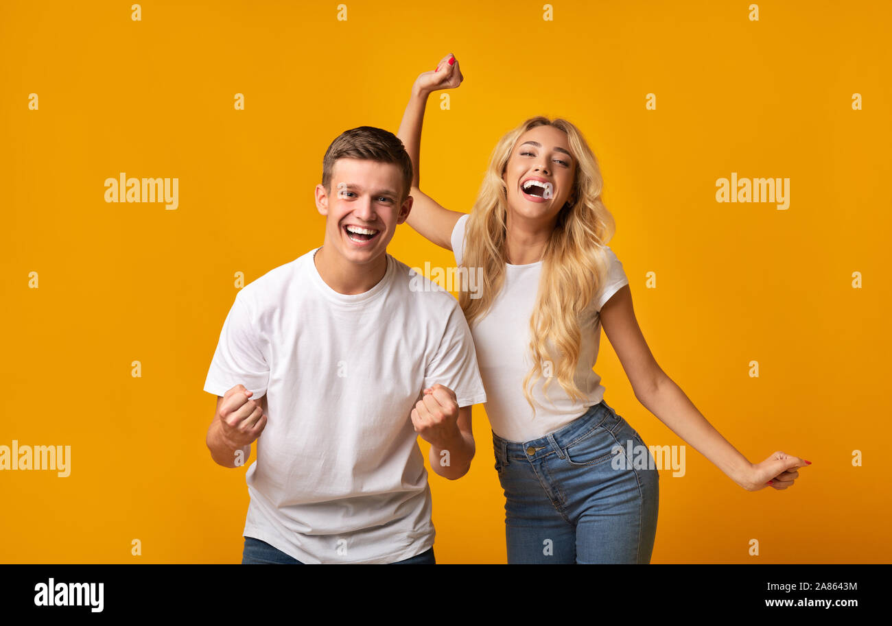 Happy millennial couple celebrating success on yellow background Stock ...