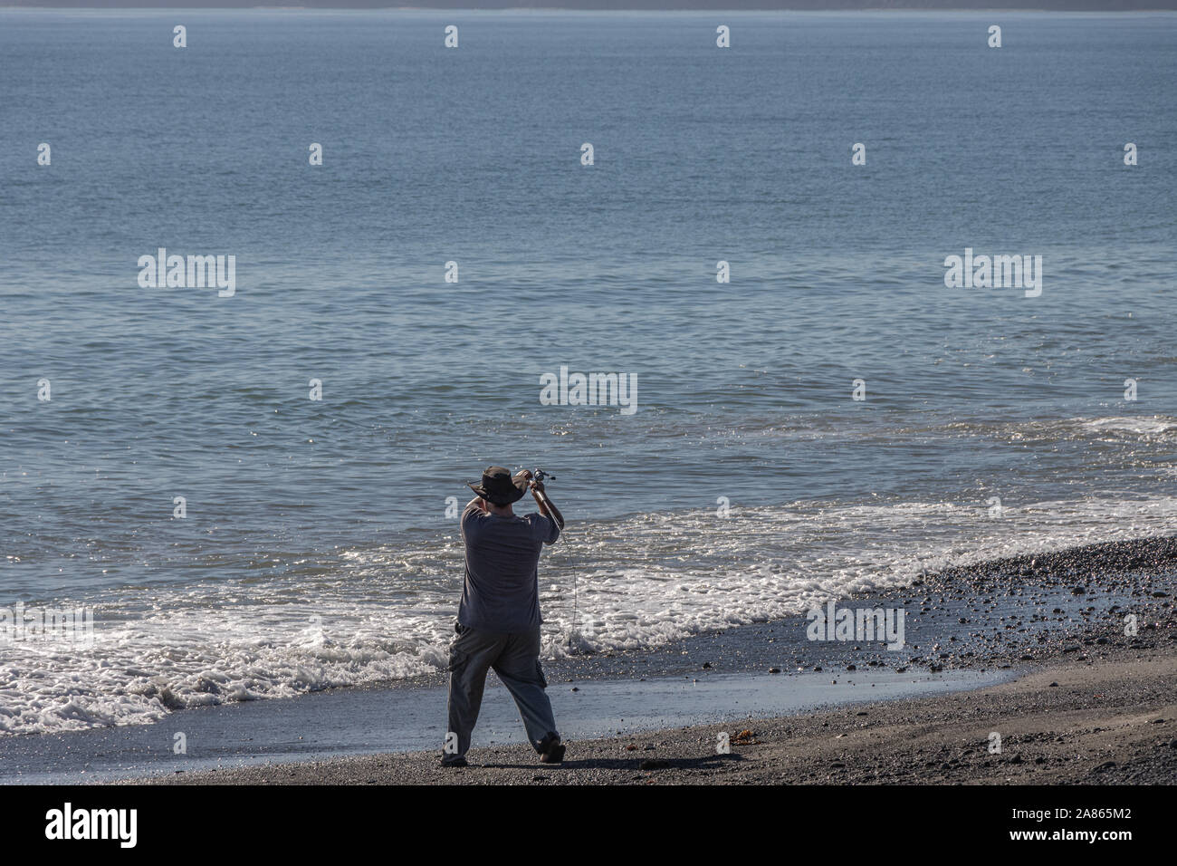 Man with fishing rod behind back ready to cast Stock Photo - Alamy