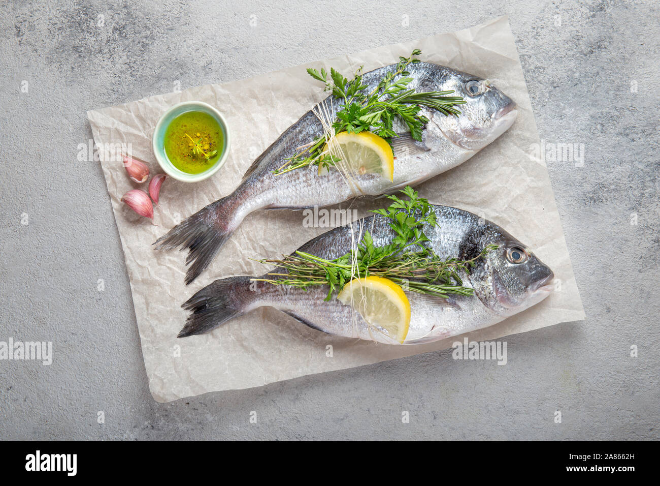 Dorada fish, raw fresh sea bream with lemon and herbs on a grey stone ...