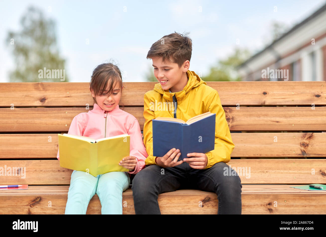 school children reading books sitting on bench Stock Photo - Alamy