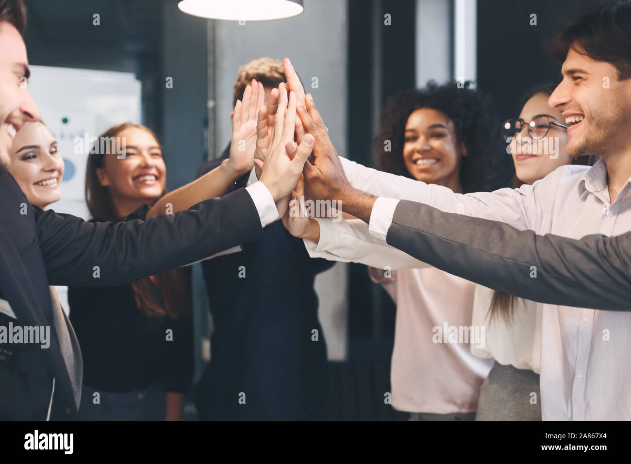 Teambuilding and unity. Happy coworkers giving high five Stock Photo ...