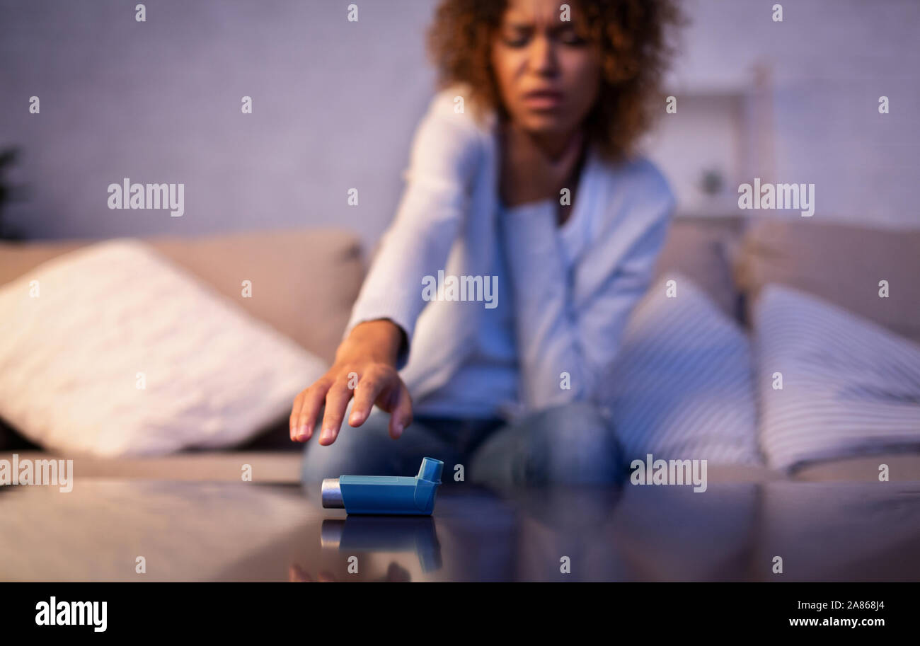Asthma attack. Young woman reaching inhaler on table Stock Photo - Alamy