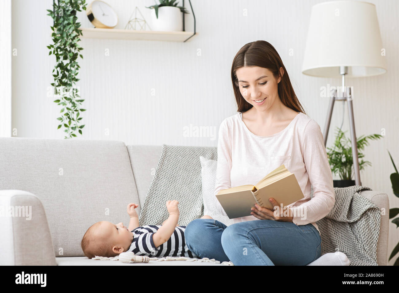 Caring mom reading book to her newborn child Stock Photo - Alamy
