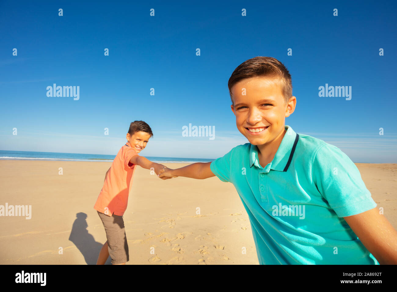 Boy pull brothers hand on the sand beach near sea Stock Photo - Alamy