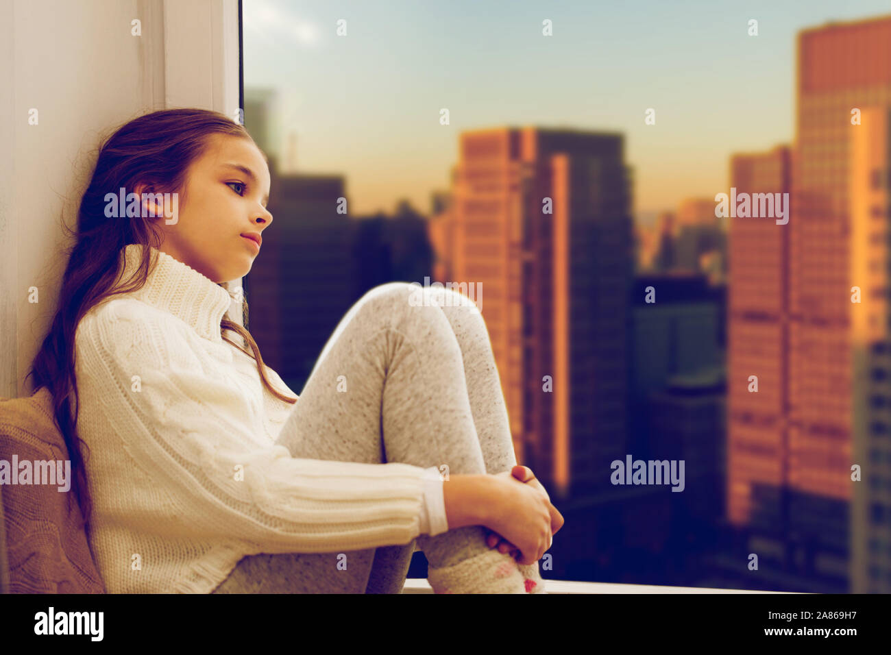 sad girl sitting on sill at home window over city Stock Photo - Alamy