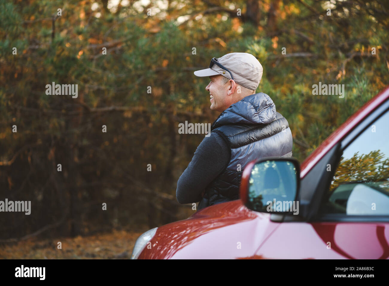 A man leans on the hood of a car. The view from the back. SUV in the ...