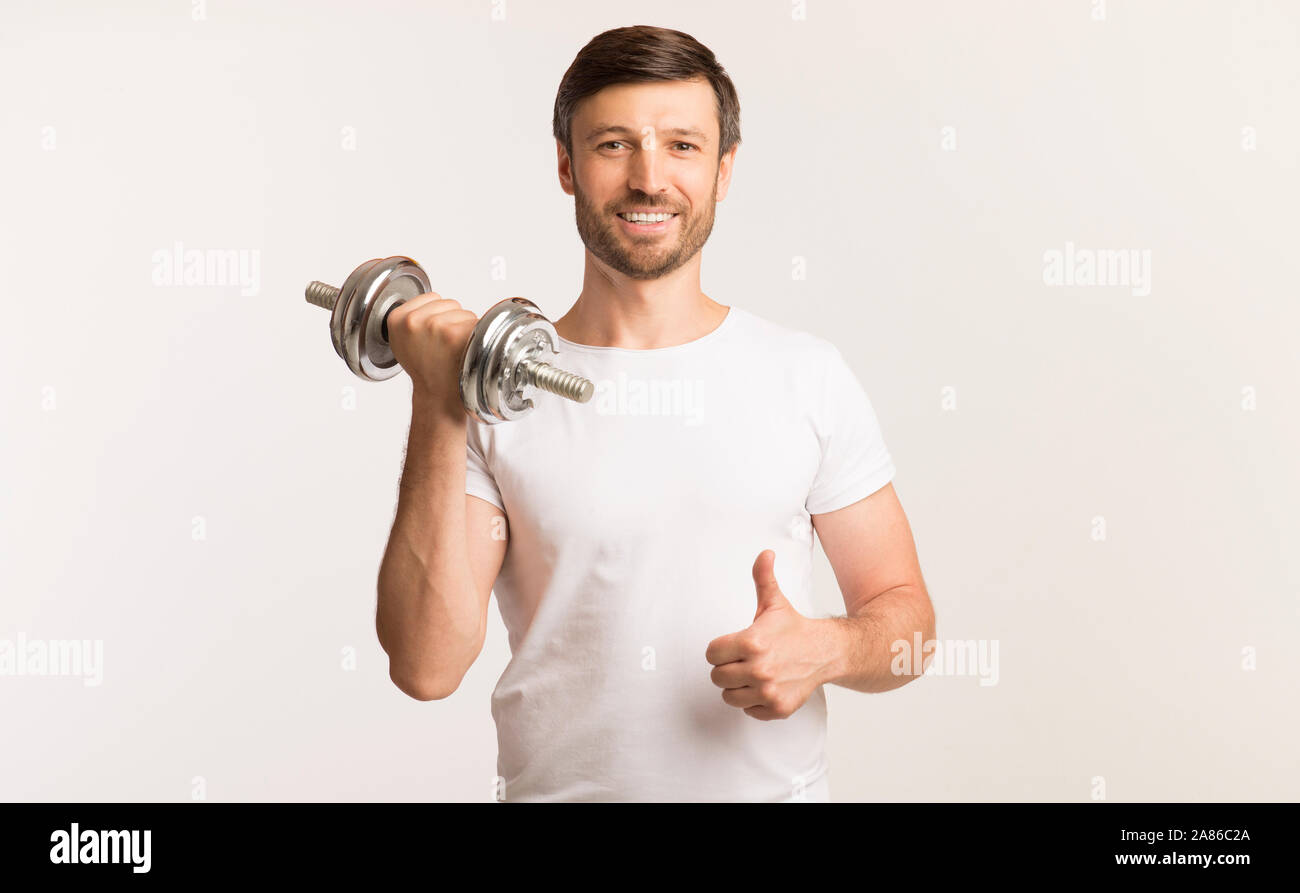 Strong Guy Holding Dumbbell Gesturing Thumbs Up, Studio Shot Stock ...