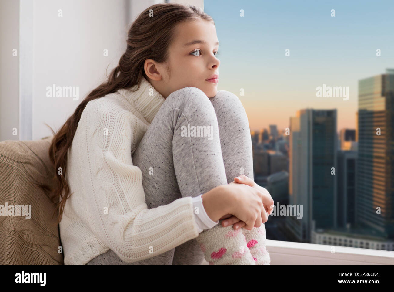 sad girl sitting on sill at home window over city Stock Photo - Alamy