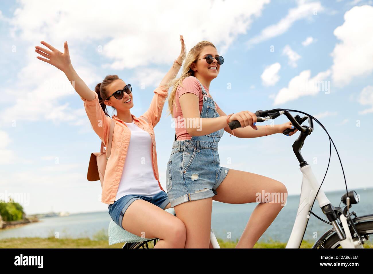 teenage girls or friends riding bicycle in summer Stock Photo - Alamy