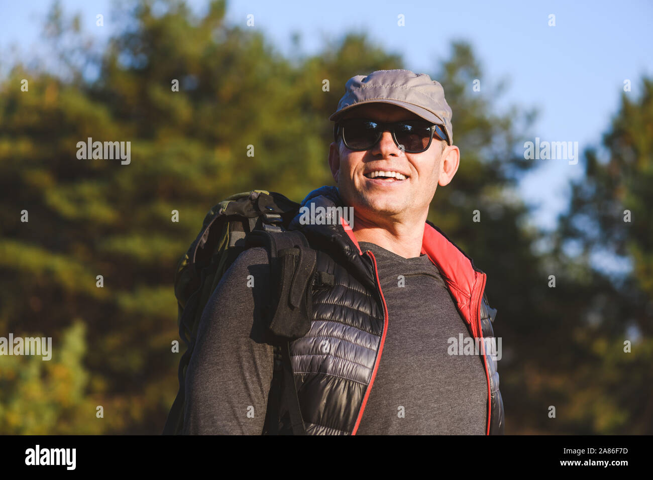 Portrait of an elderly man with a backpack on a forest background. A ...