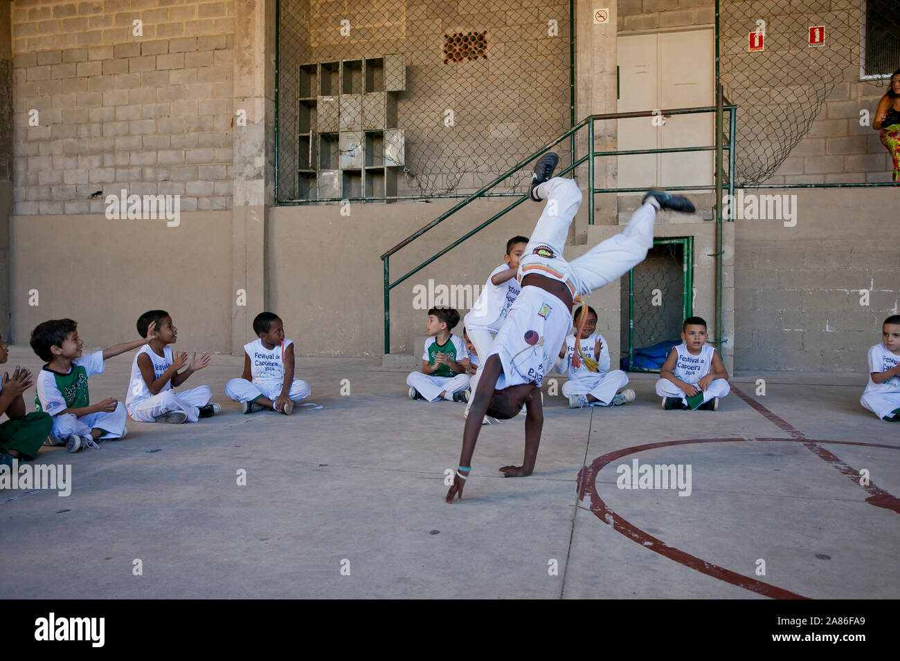 Kids at a Brazilian capoeira class with a teacher playing a berimbau ...