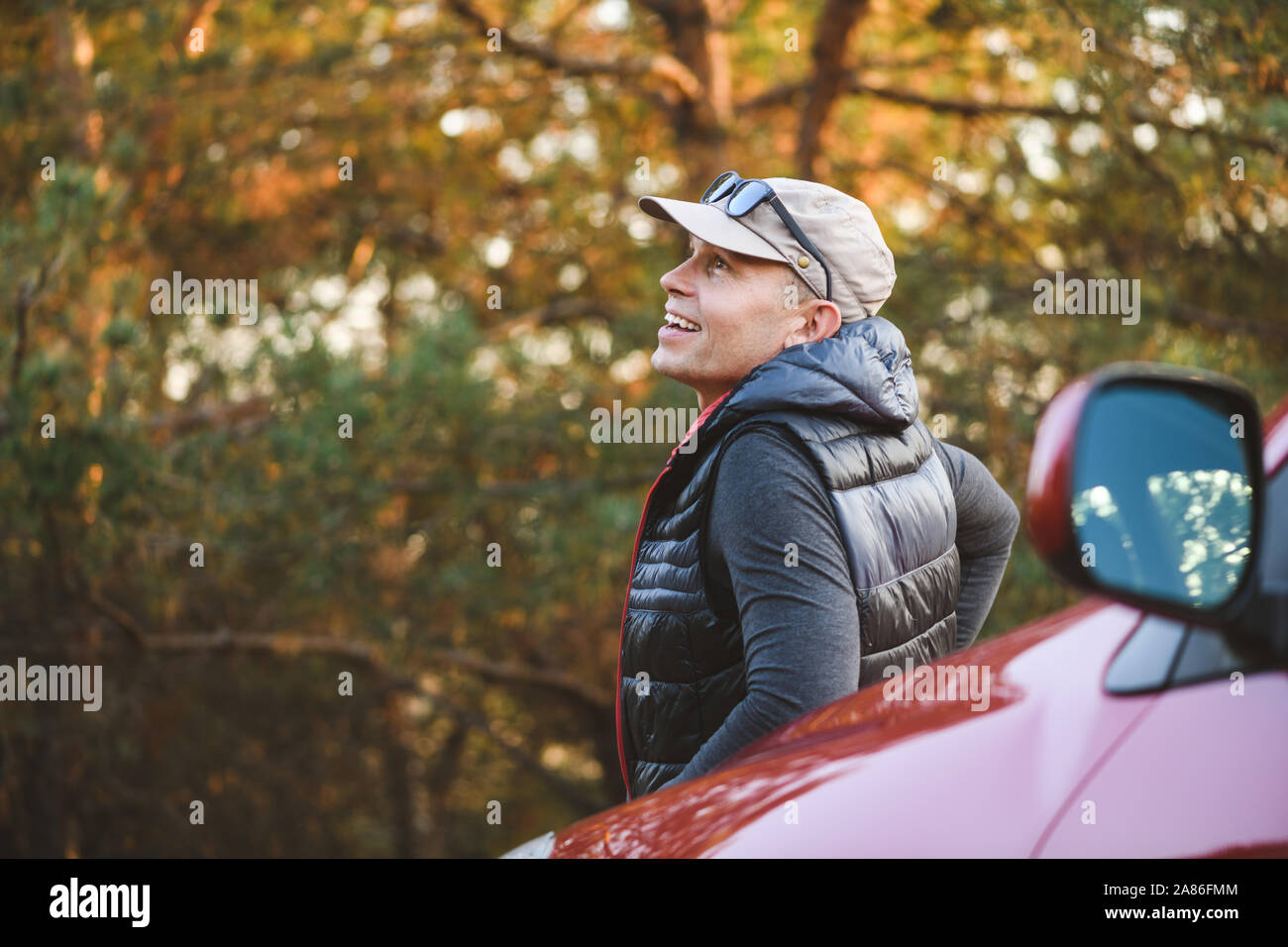 Happy tourist lean on car from back. A man leans on the hood of a car ...