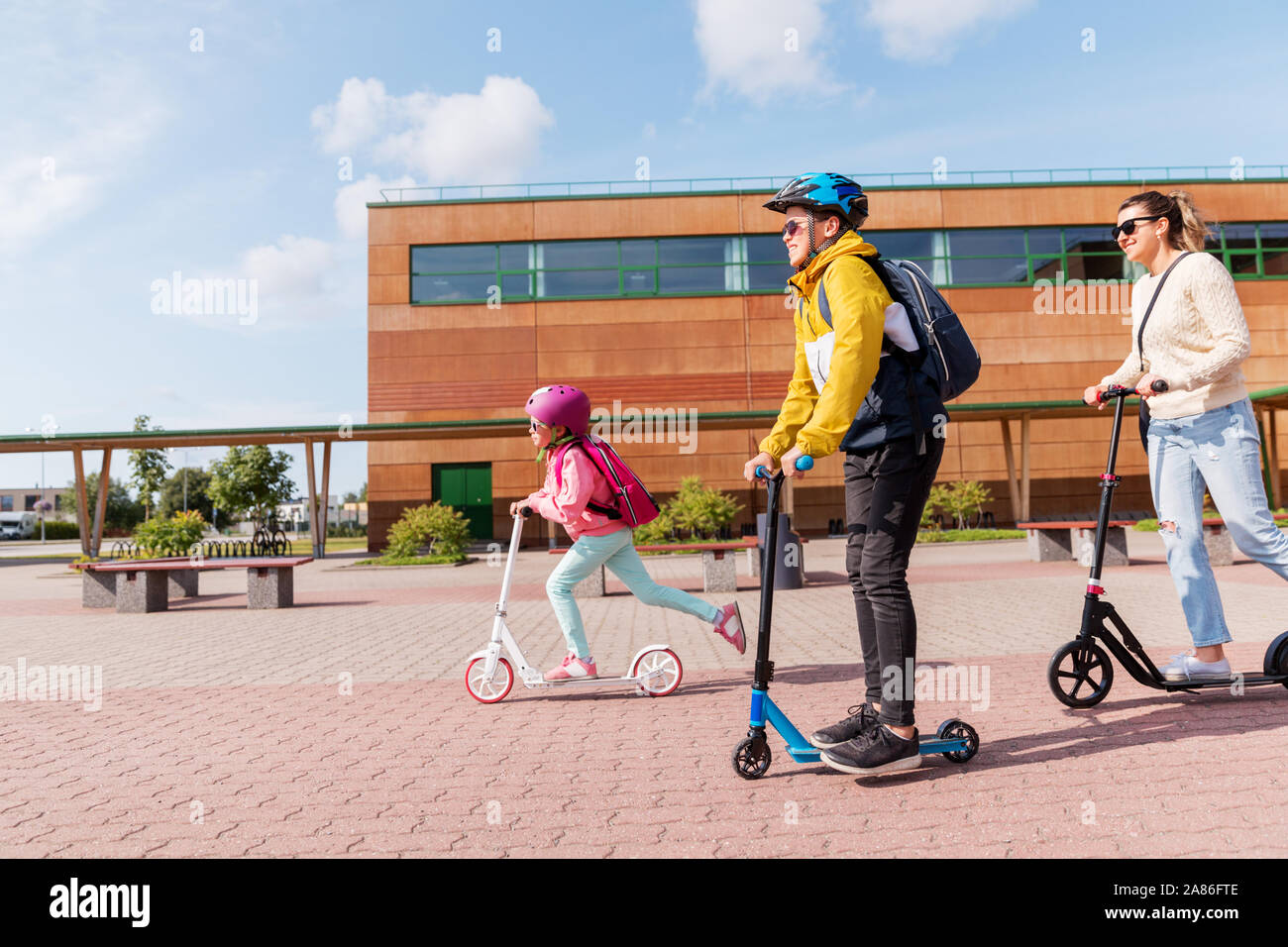 happy school children with mother riding scooters Stock Photo - Alamy