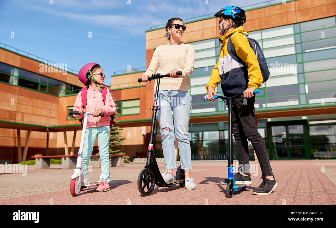 happy school children with mother riding scooters Stock Photo - Alamy