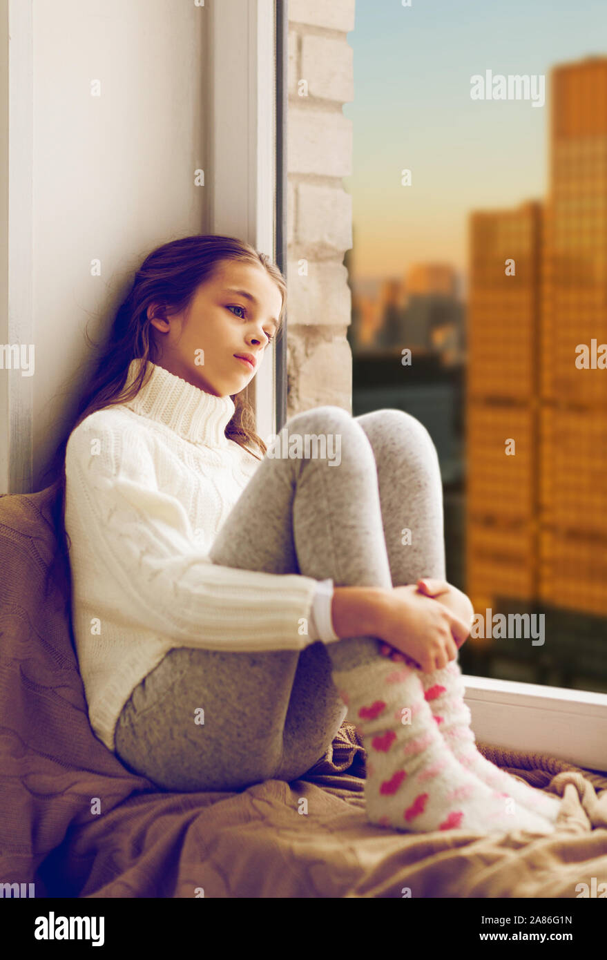 sad girl sitting on sill at home window over city Stock Photo - Alamy