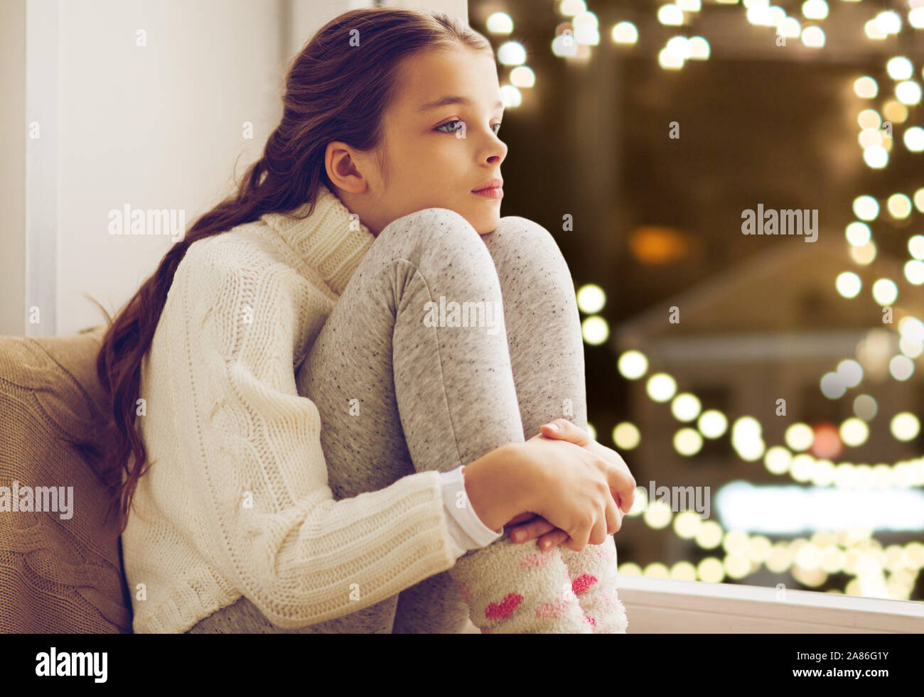 sad girl sitting at home window on christmas Stock Photo - Alamy
