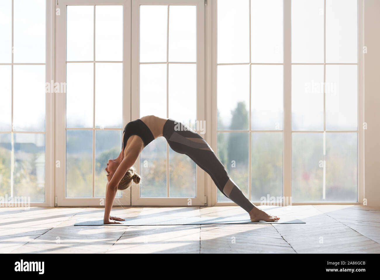 Acrobatic girl making bridge over big panoramic window Stock Photo - Alamy