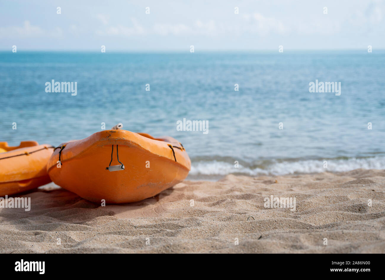 Two colorful orange kayaks on a sandy beach ready for paddlers in sunny ...