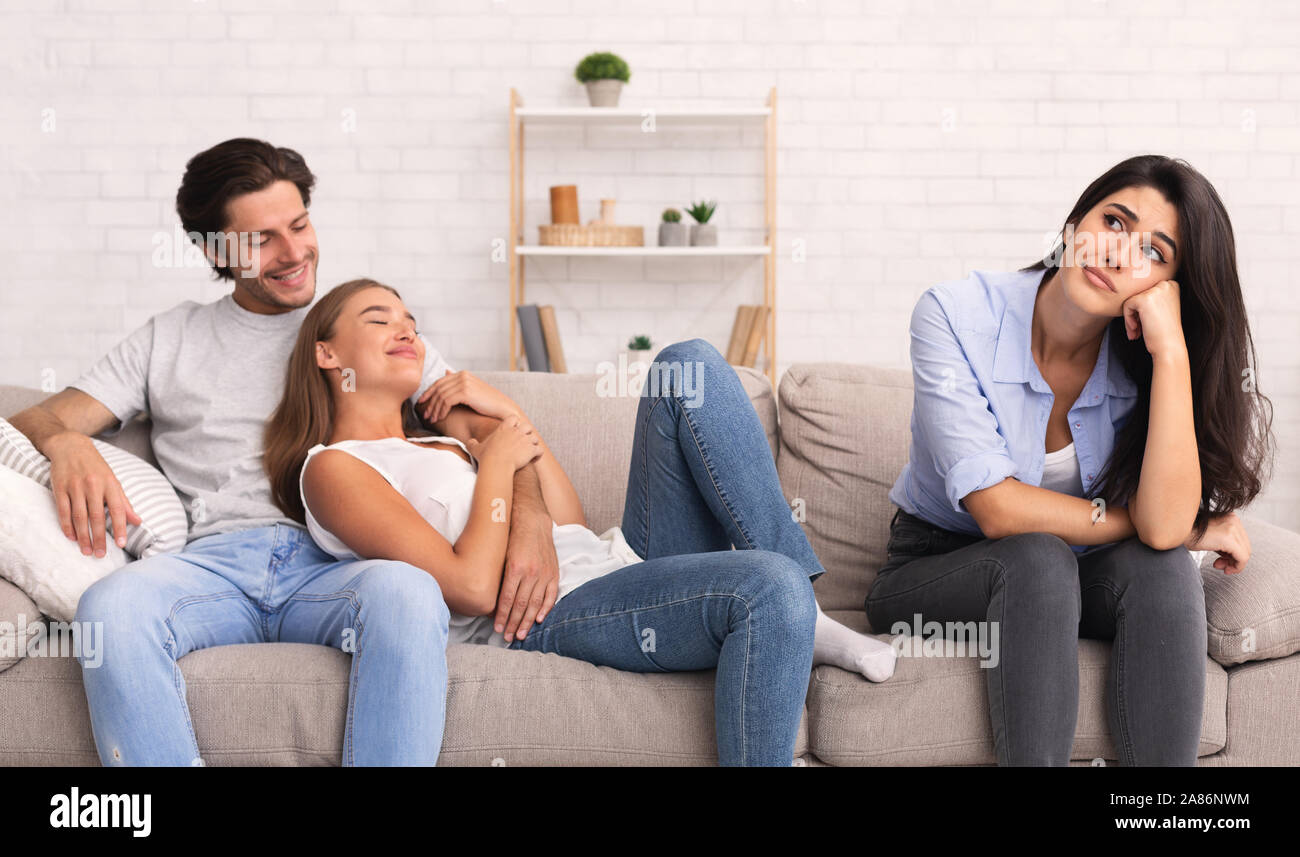 Bored Girl Sitting With Friends Hugging On Couch At Home Stock Photo ...