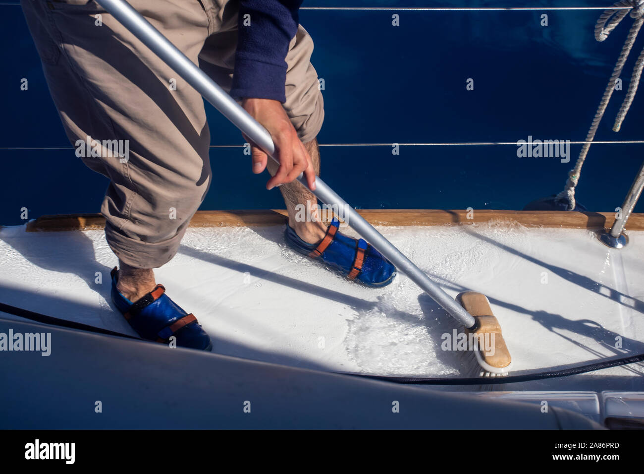 A man mops the deck of a yacht Stock Photo - Alamy