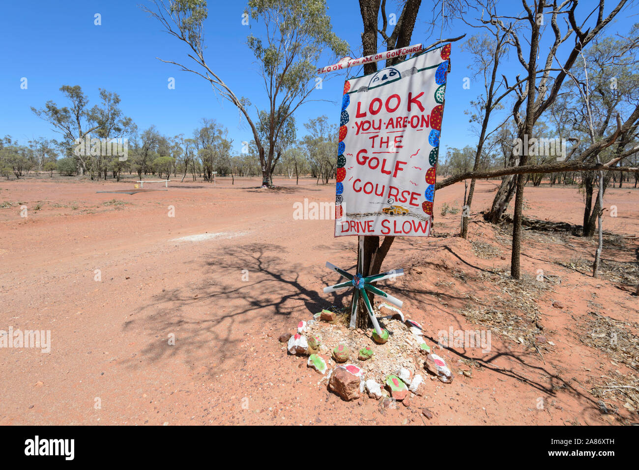 Warning sign of a golf course in the red dust of the Outback, the ...