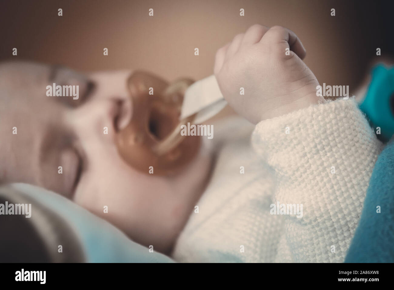 Beautiful little newborn sleeping sucking the pacifier. Focus on the ...