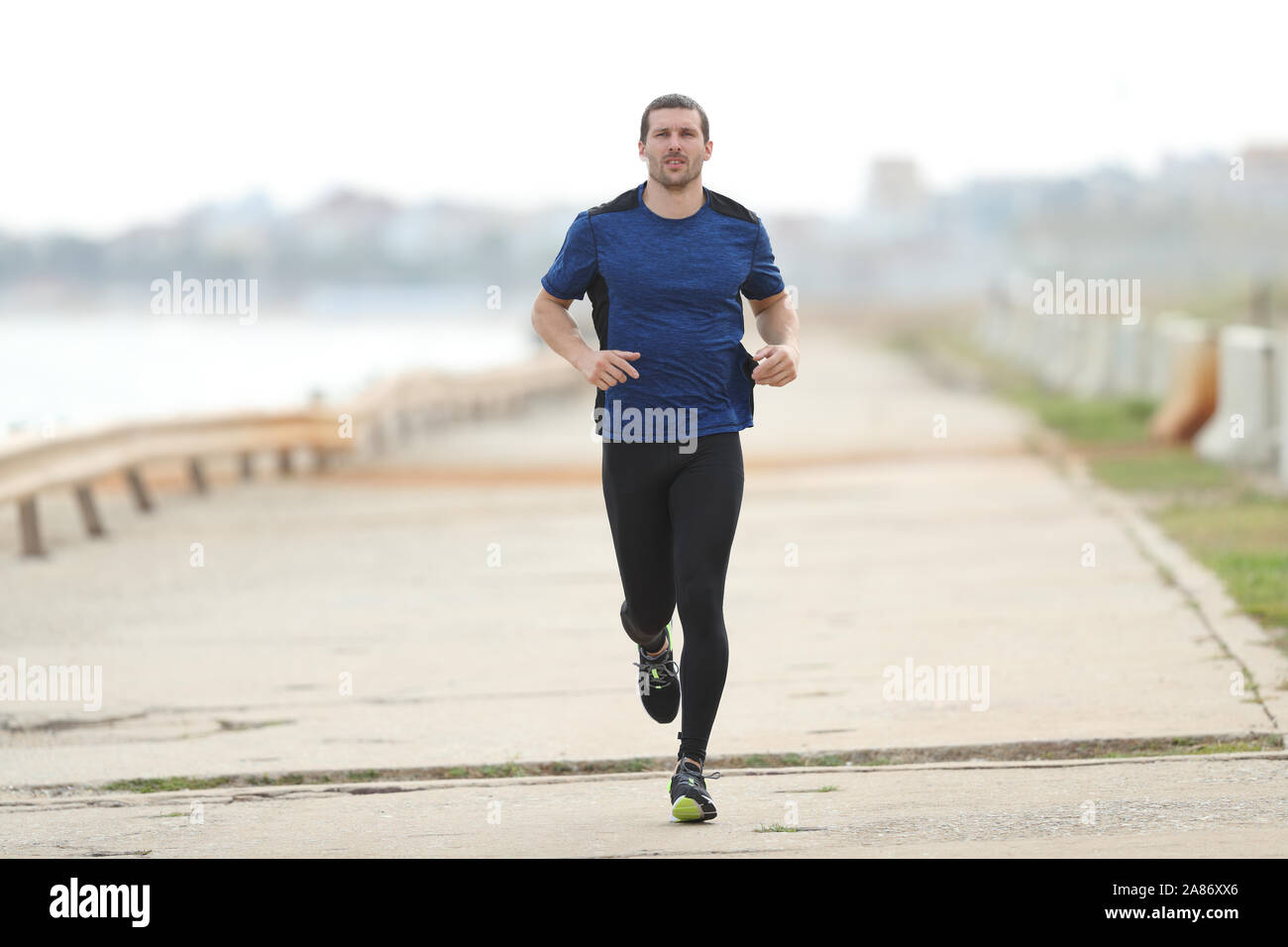 Runner training running towards camera on a concrete way Stock Photo ...