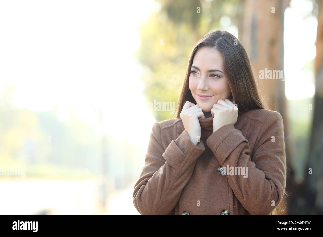 Front view portrait of an satisfied woman heating in a park in winter ...