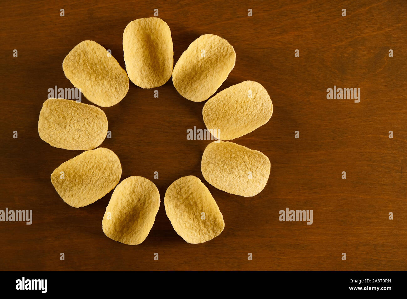 sun or flower shaped potato chips on a wooden table, top view with copy ...