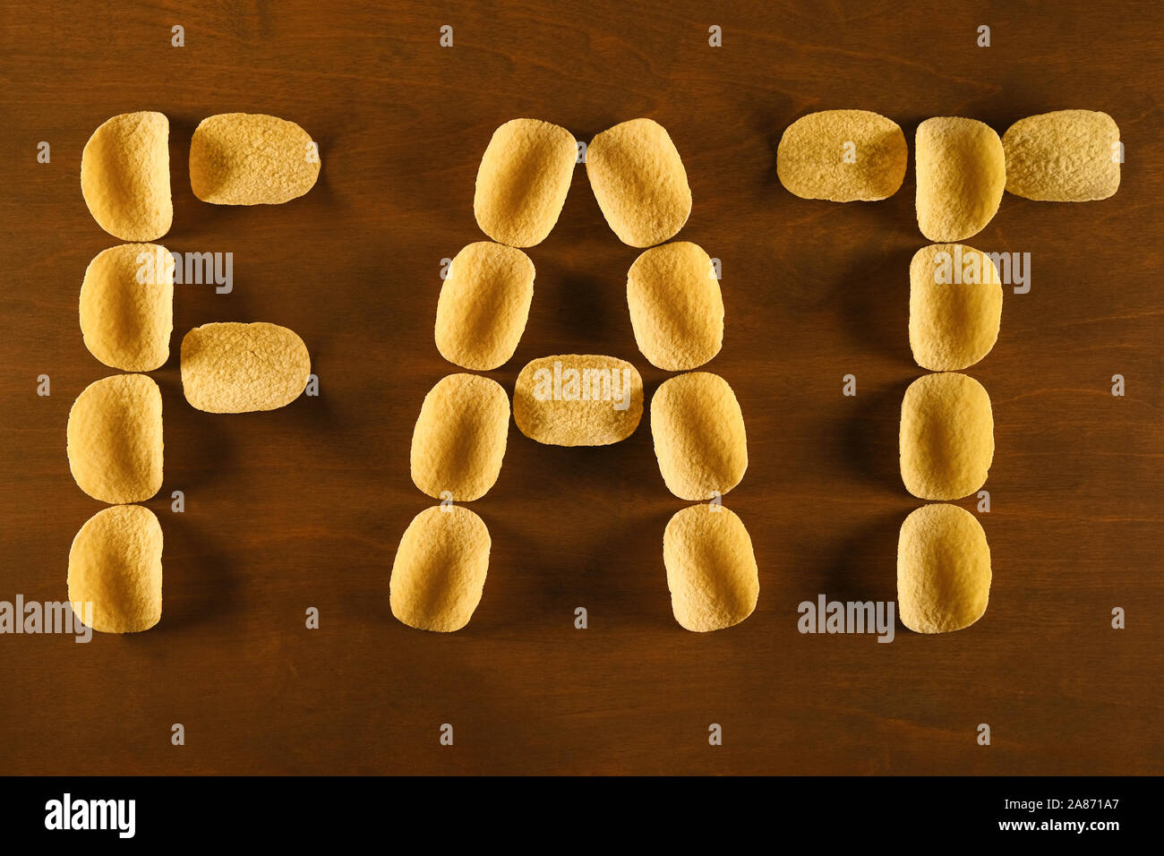 potato chips on a wooden table, background with text “FAT”, design ...