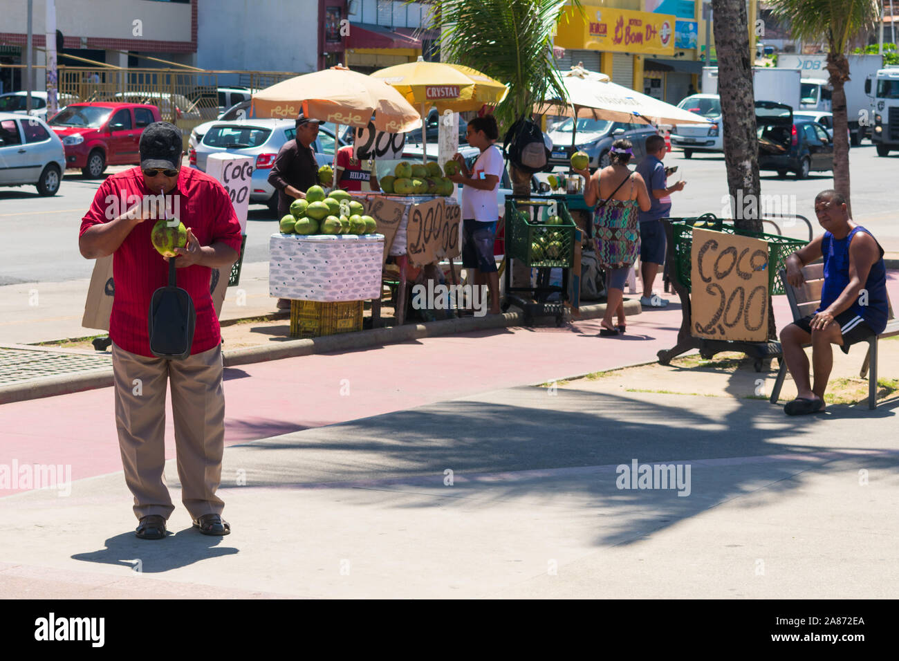 Afro Brazilian man drinking coconut water with many cheap coconut water ...