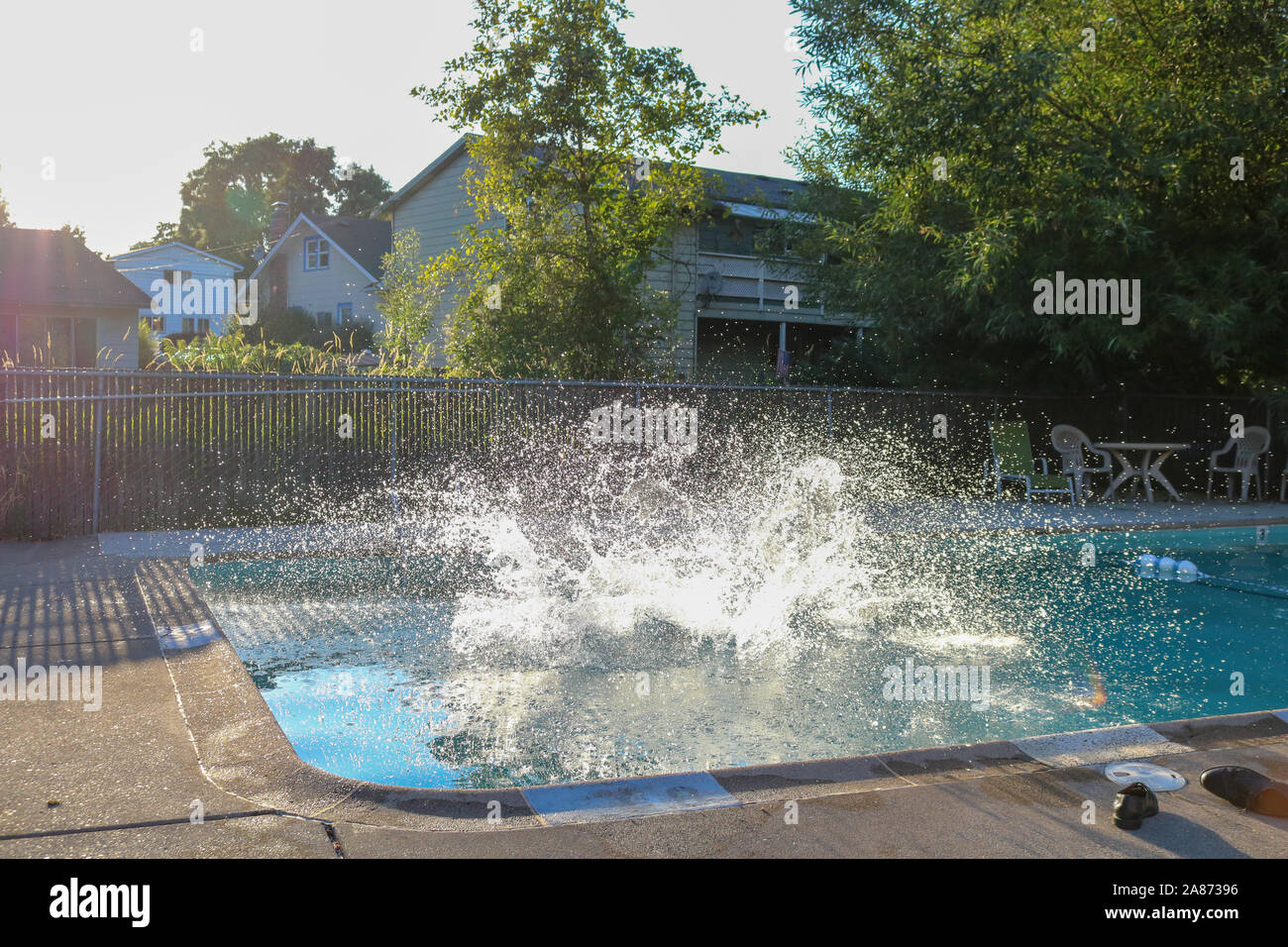 An action shot of the splash created by jumping into a pool on a summer ...