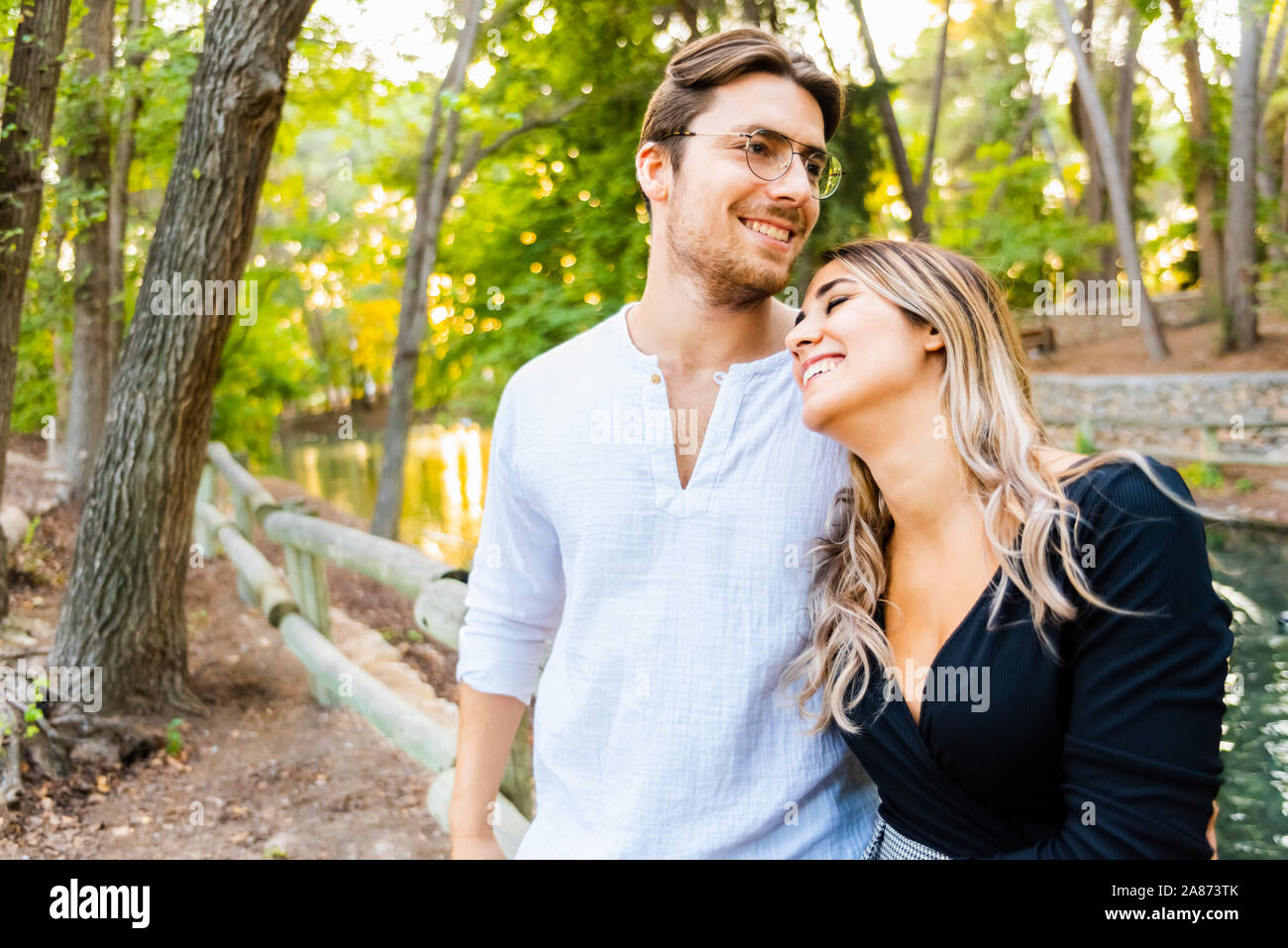 Couple of friends flirting fun while hugging on a walk in a natural ...