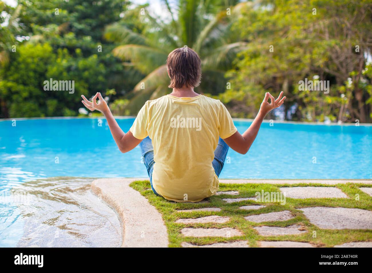 Young man sitting in the lotus position near the pool Stock Photo - Alamy