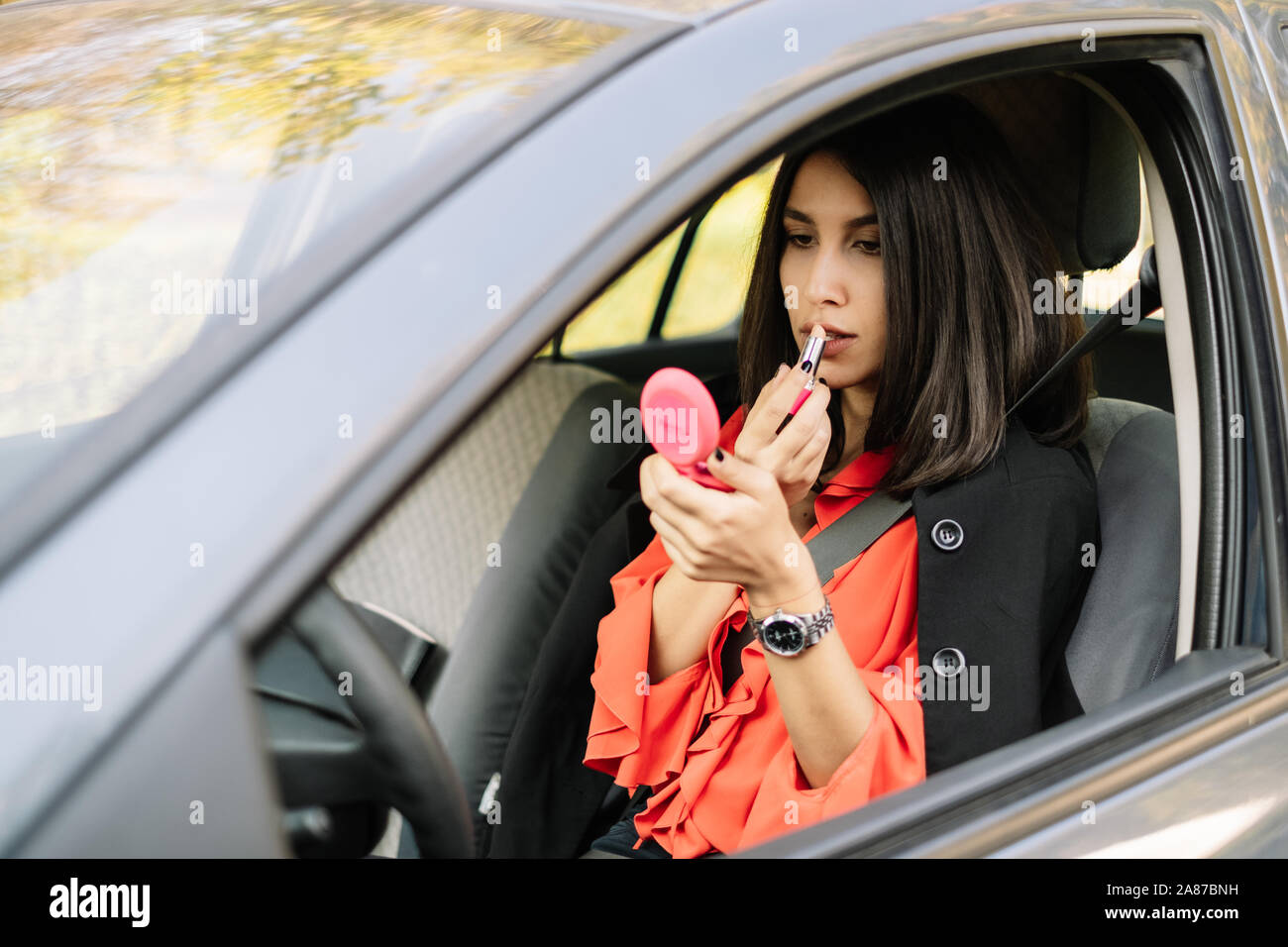 Beautiful woman applying makeup in a car Stock Photo - Alamy