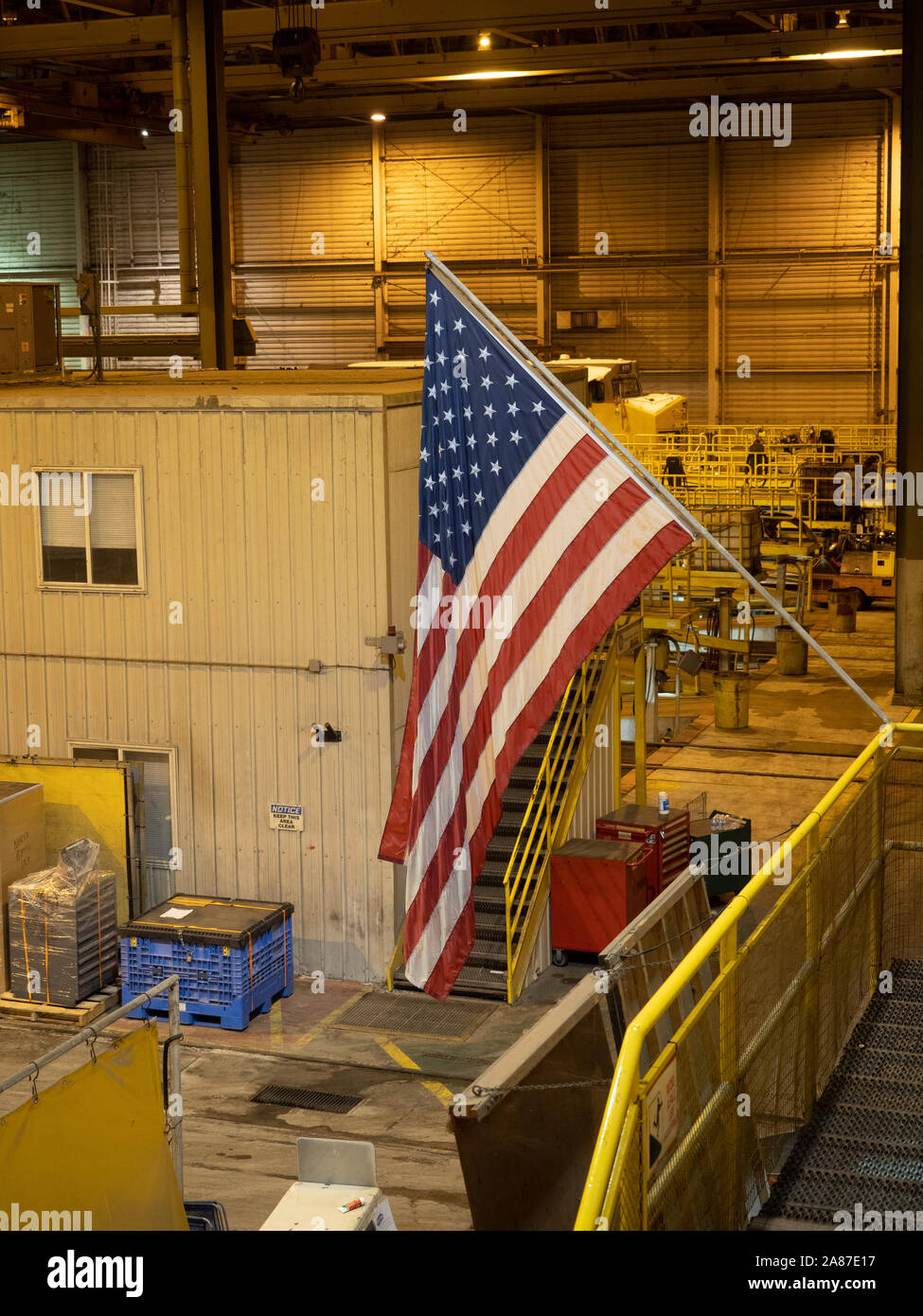 American flag hanging indoors in a factory with tools and storage ...