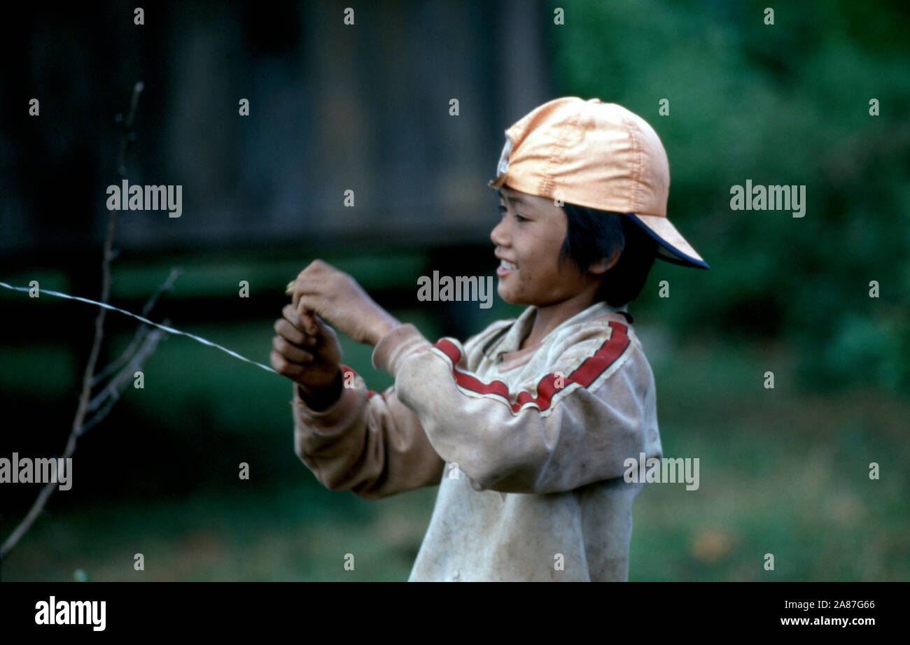 A young, indigenous Mnong (Pnong) boy flying a kite in his remote ...