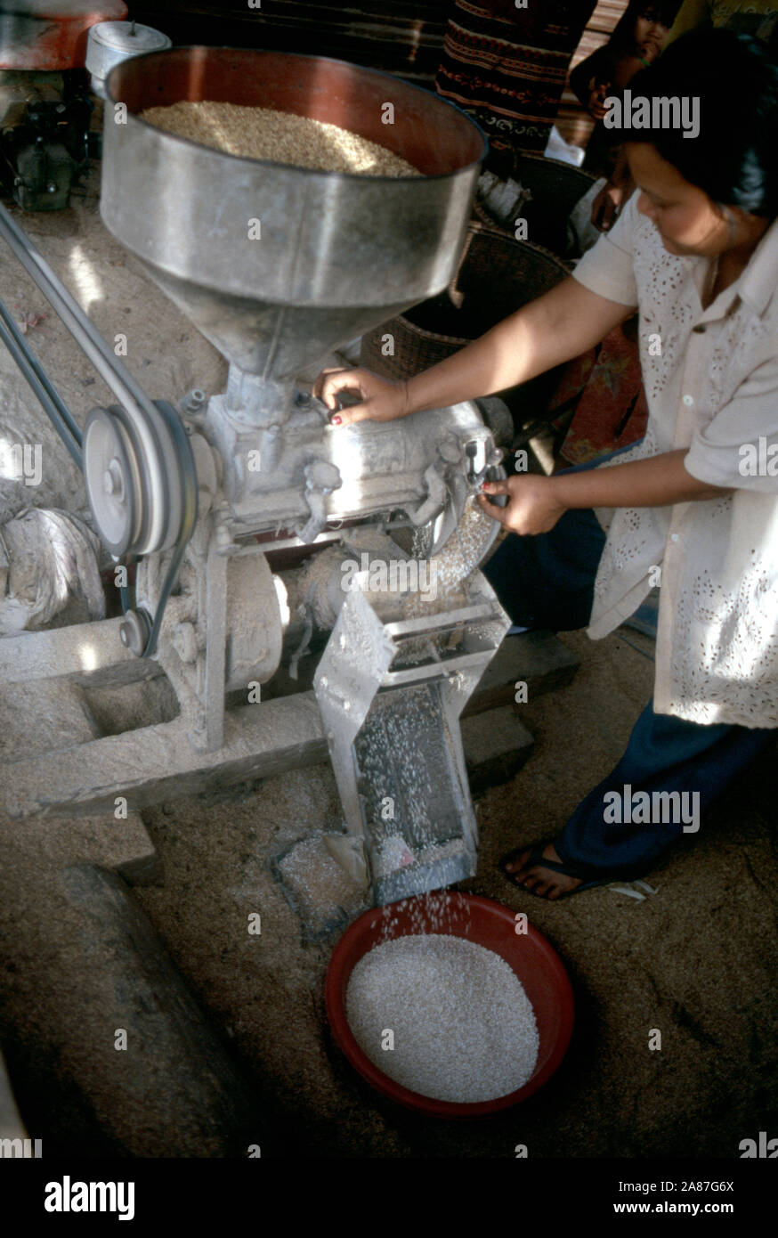 An indigenous Mnong (Pnong) woman uses a diesel-powered machine to husk ...